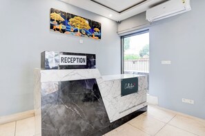 Bancada de recepção com superfície de mármore, placa com a palavra 'RECEPTION' e placa com a palavra 'Collection'.