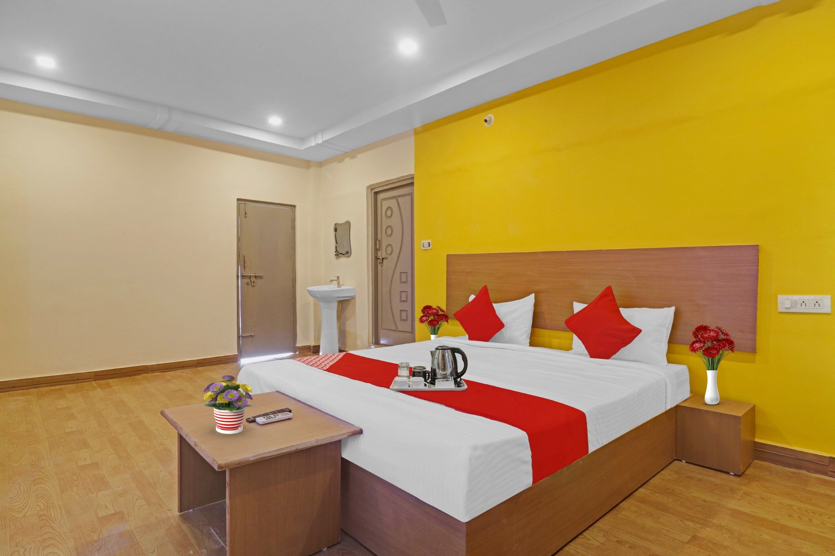 Quarto de hotel com cama, mesa de cabeceira e uma pequena mesa com um vaso de flores.