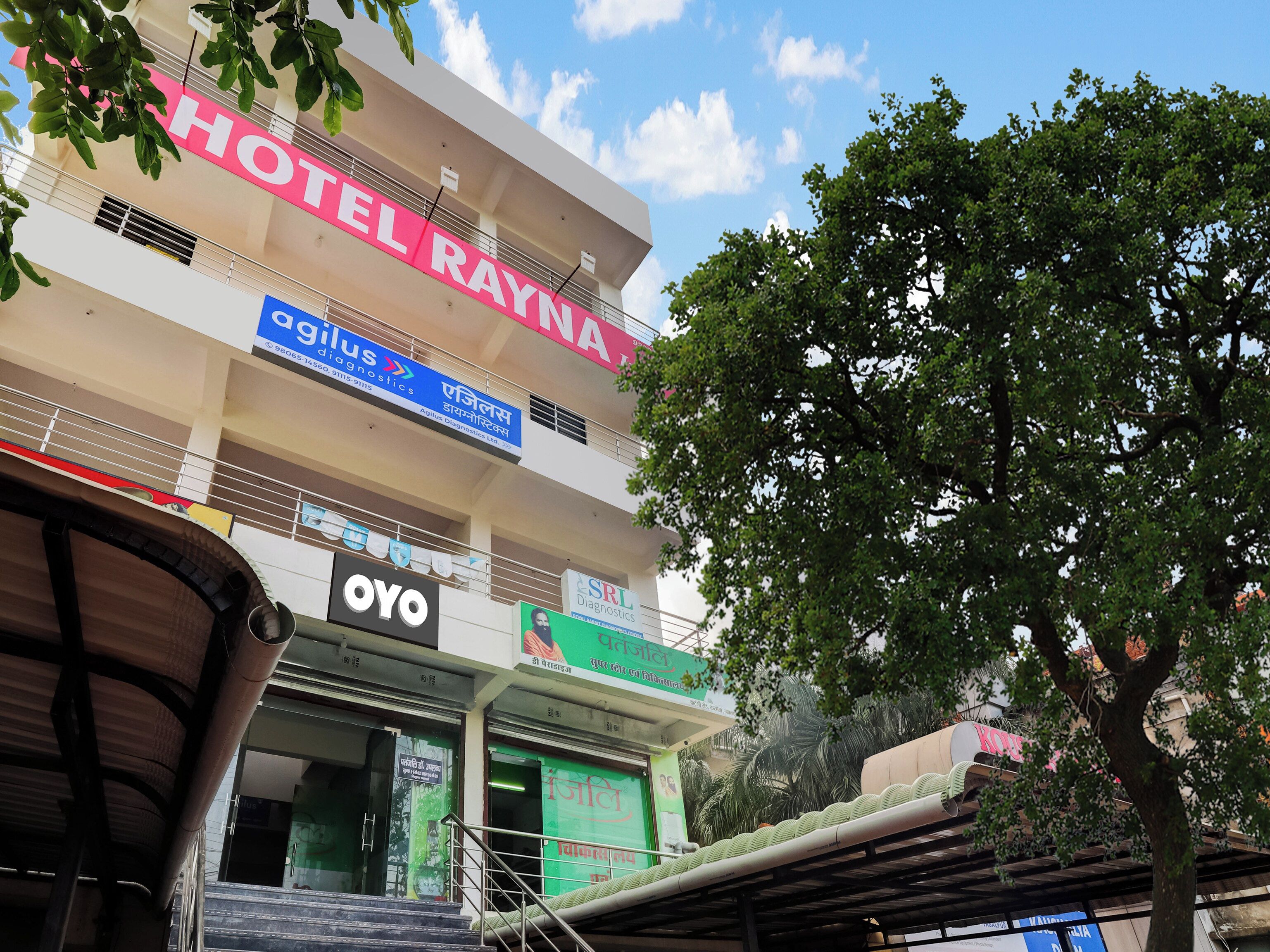 Um edifício de vários andares com um letreiro chamativo 'HOTEL RAYNA'.