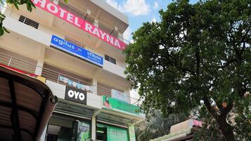 Um edifício de vários andares com um letreiro chamativo 'HOTEL RAYNA'.