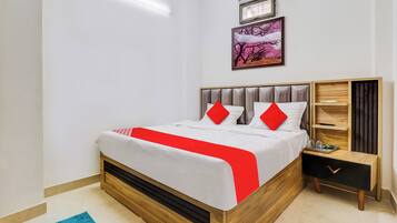 Quarto de hotel com cama, mesa de cabeceira e ar condicionado fixado na parede.