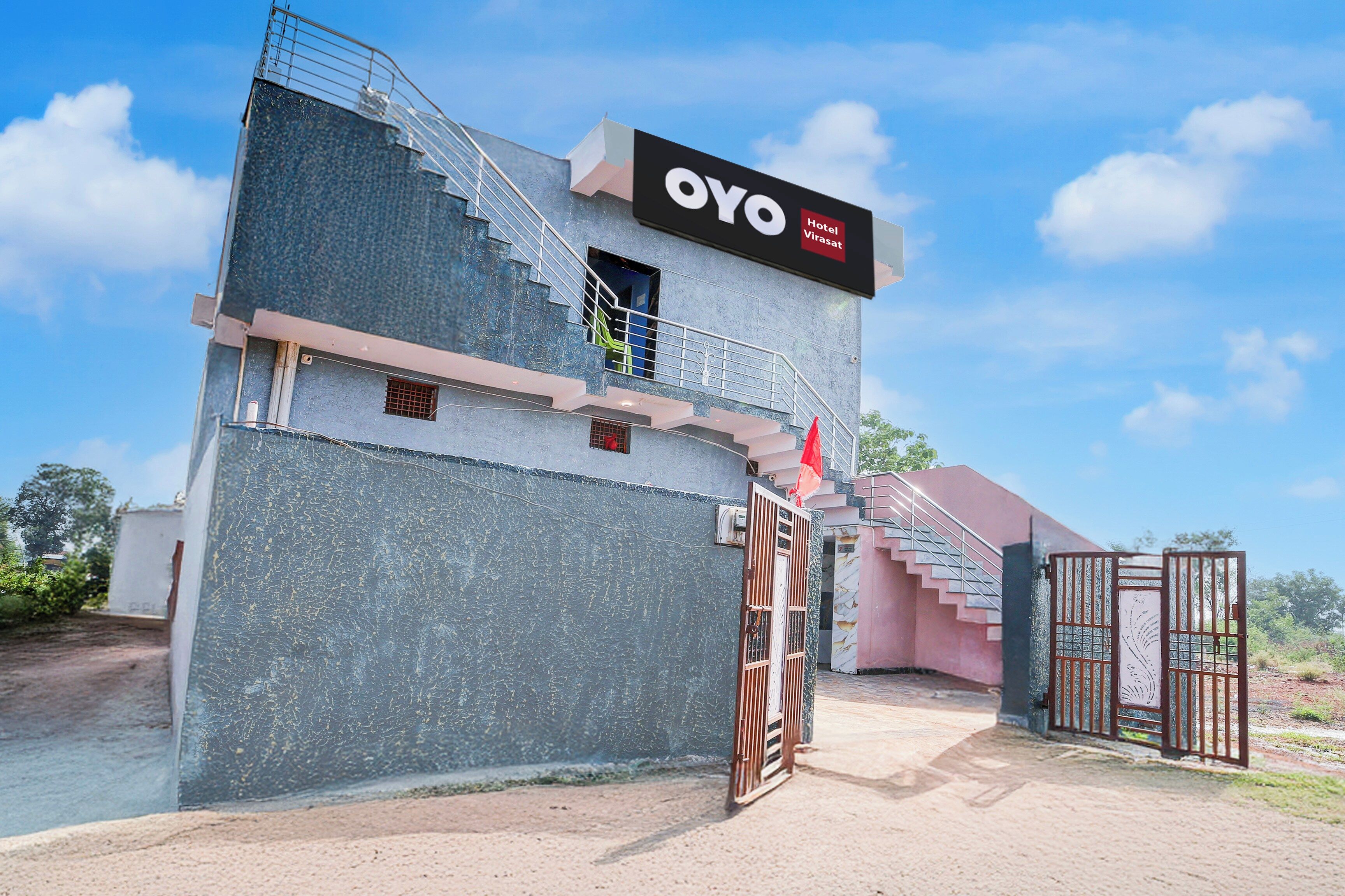 Um edifício com uma placa indicando 'OYO Hotel Virasat' e uma entrada gradeada.