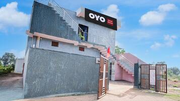 Um edifício com uma placa indicando 'OYO Hotel Virasat' e uma entrada gradeada.