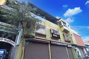 Um edifício com uma placa indicando 'OYO' e uma placa parcialmente visível com texto em um alfabeto não latino.