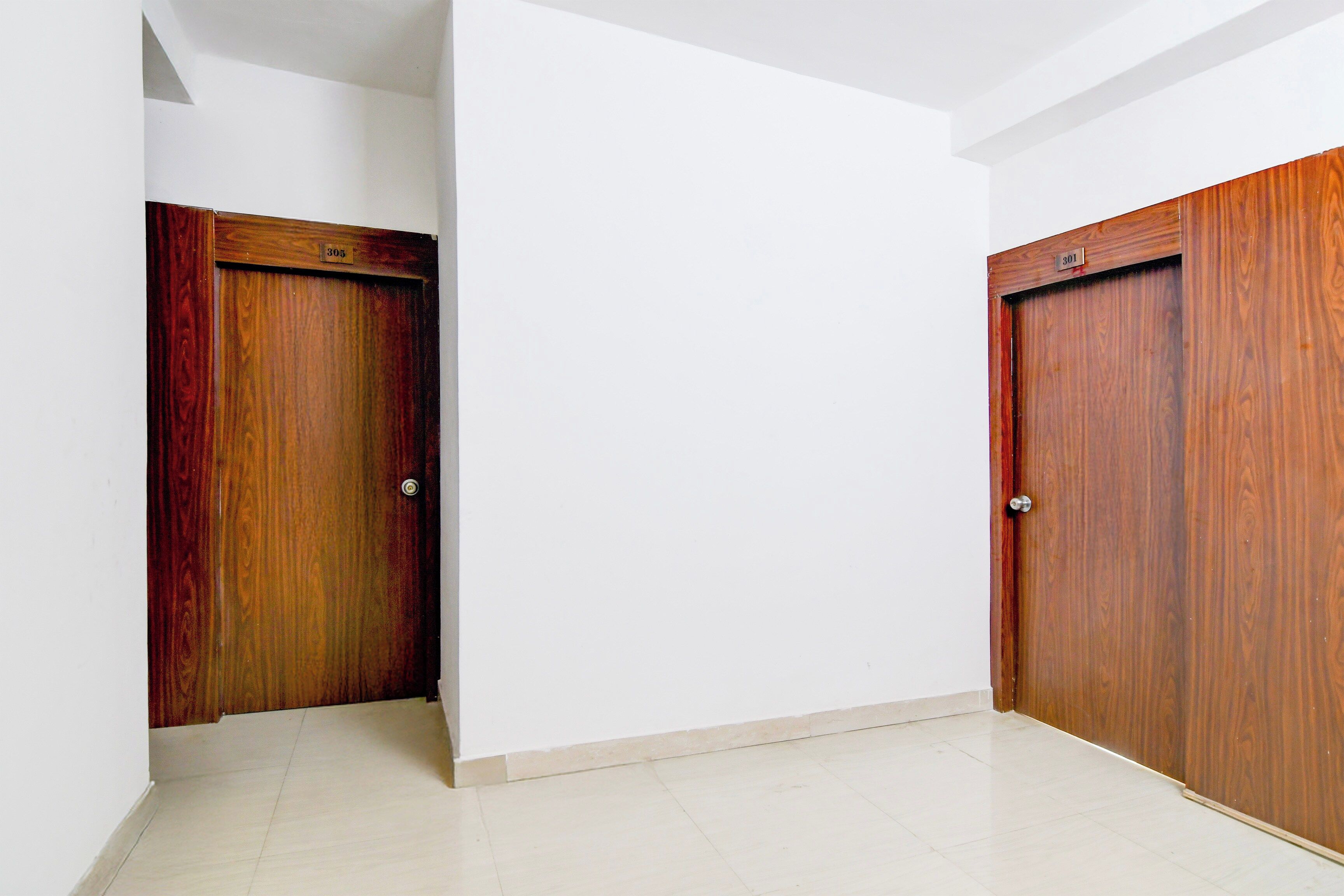 Corredor com duas portas de madeira, uma com a placa 305 e a outra com 301, dando acesso a quartos.