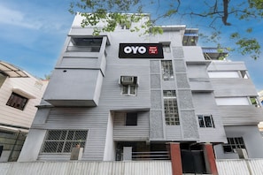 Um hotel moderno com um letreiro chamativo que diz 'OYO Hotel City of Joy'.