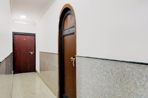 Um corredor com porta de madeira e parede de mármore.