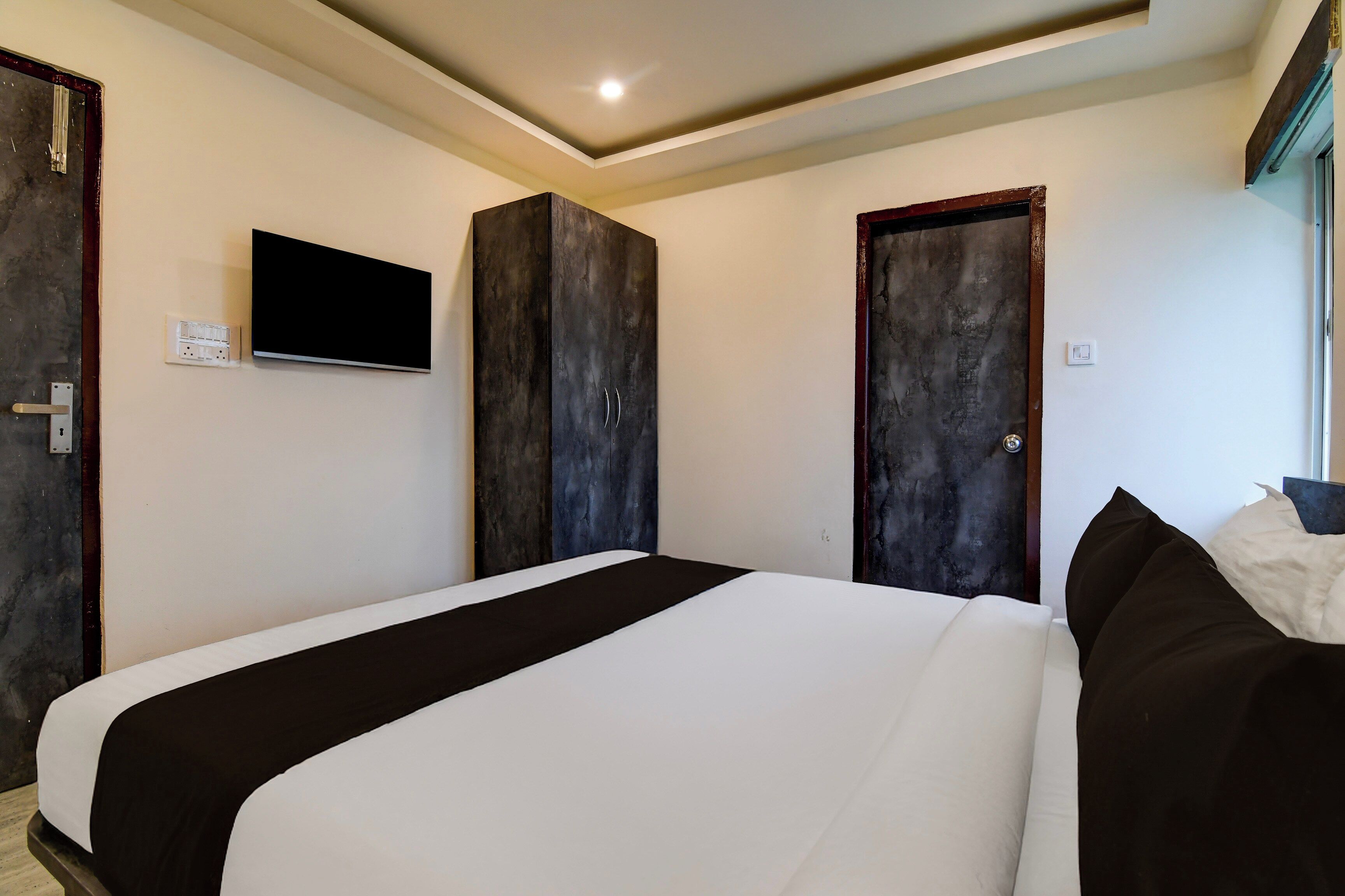 Quarto de hotel com cama, televisão de tela plana na parede e duas portas.