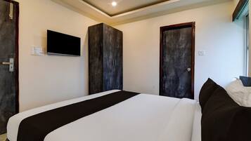Quarto de hotel com cama, televisão de tela plana na parede e duas portas.