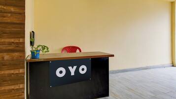 Balcão de recepção com a palavra 'OYO', uma planta em vaso e uma cadeira vermelha.