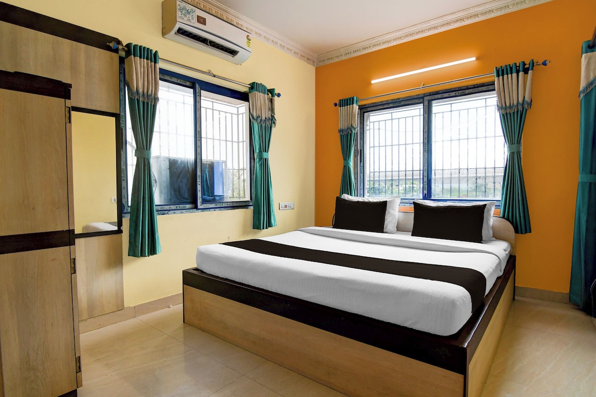 Quarto de hotel com cama, cortinas, ar condicionado e janela.