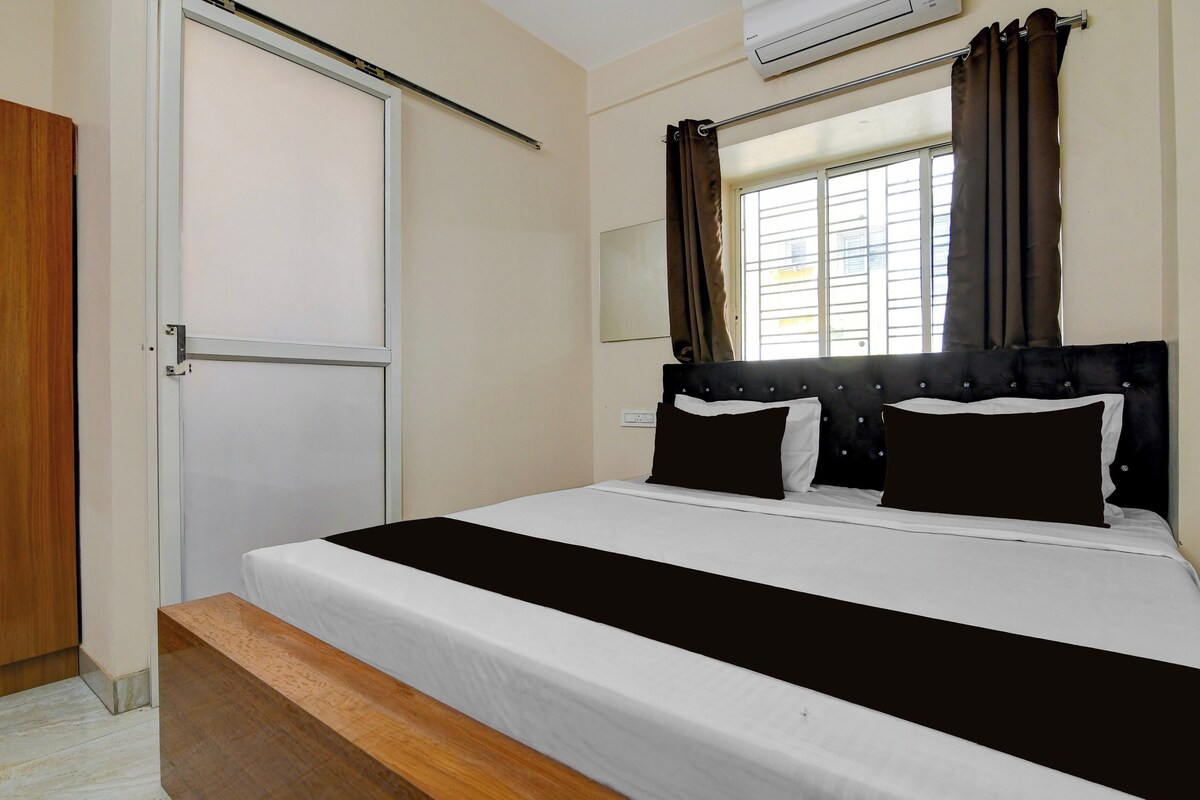 Quarto com cama, guarda-roupa, janela com cortinas e ar condicionado.