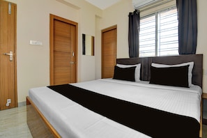 Quarto com cama, guarda-roupa de madeira e janela com cortinas.