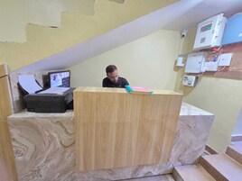 Quarto com escrivaninha, computador e pequena estante.