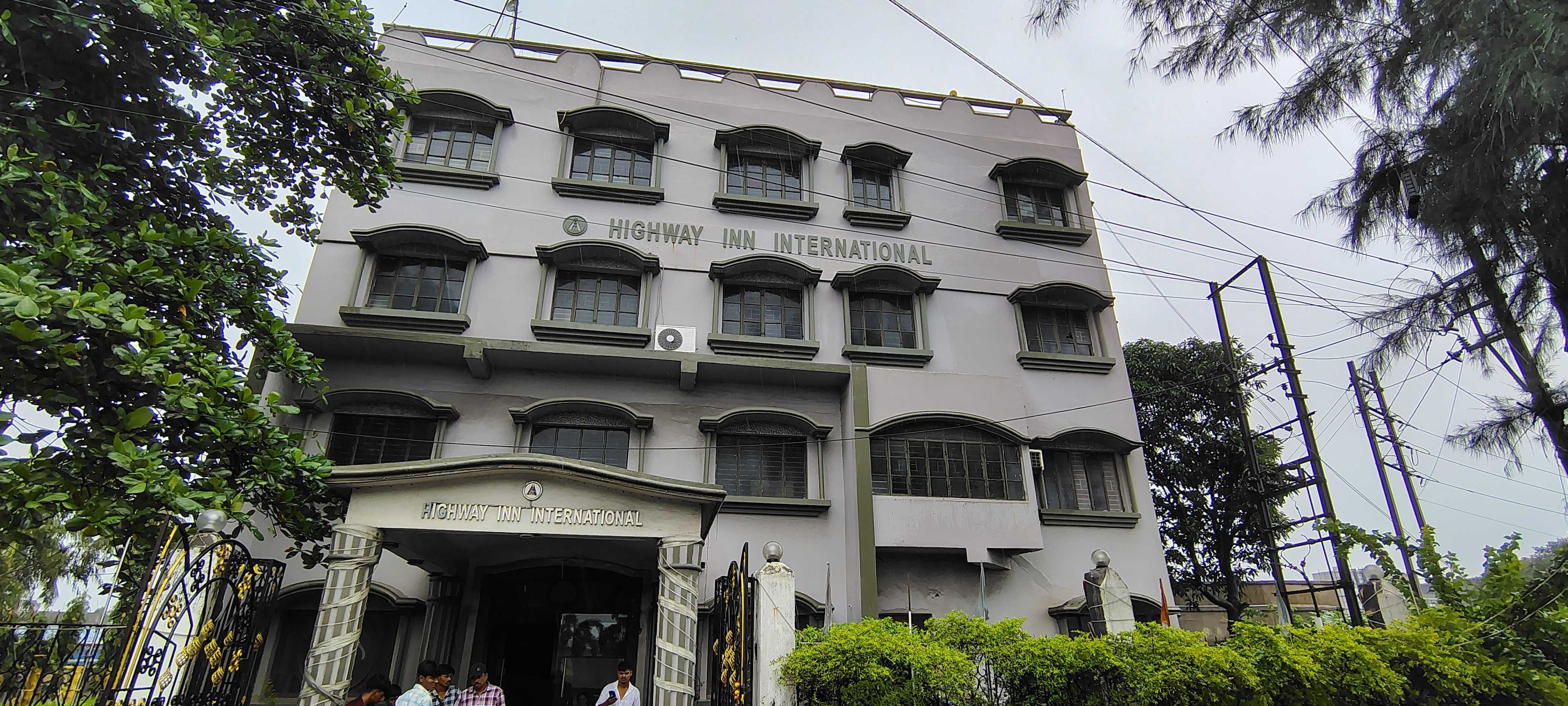 Um edifício de vários andares com uma placa de entrada que diz 'HIGHWAY INN INTERNATIONAL'.