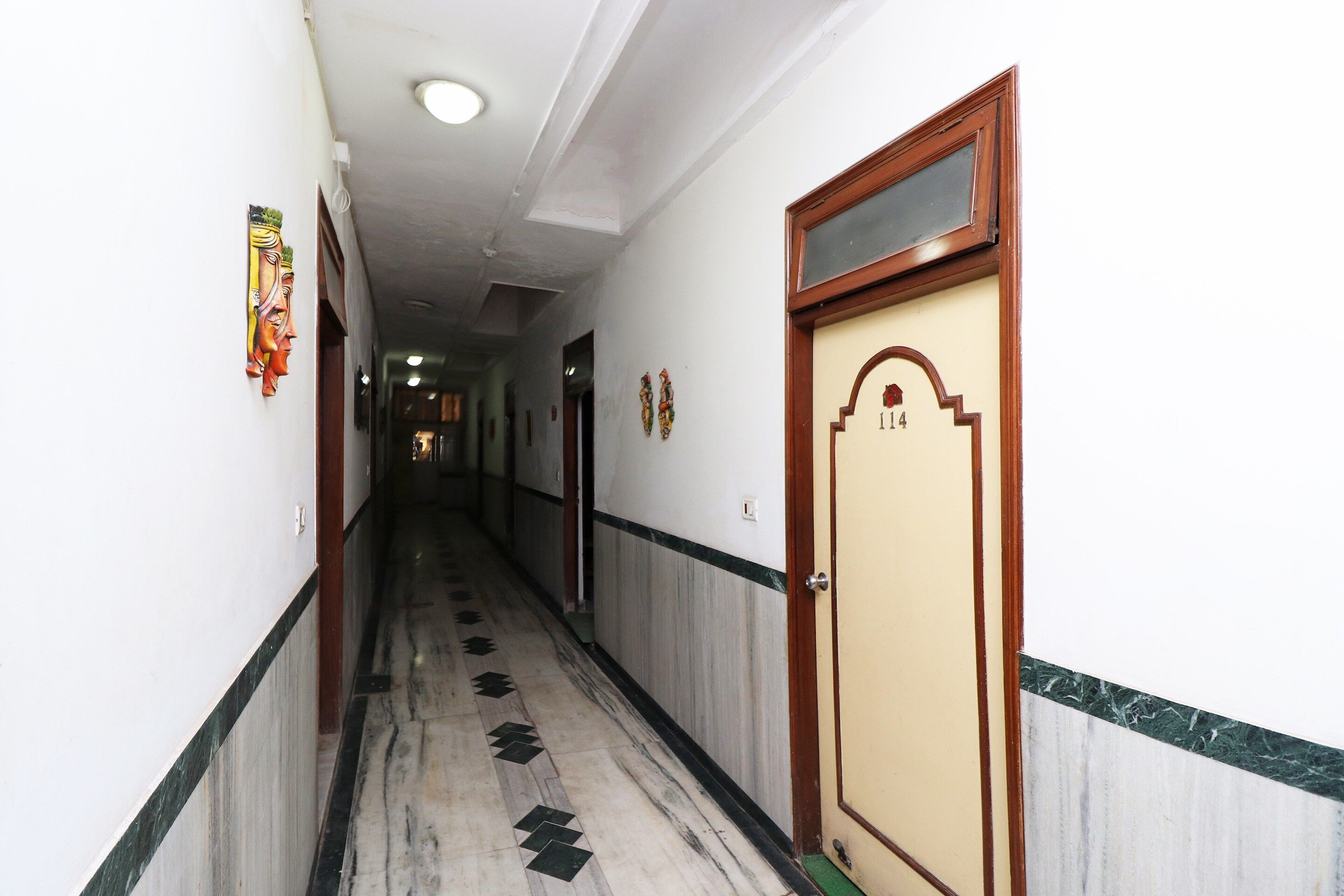 Um corredor com piso de mármore, portas e decorações nas paredes.