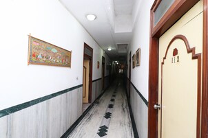 Corredor com portas em ambos os lados, piso estampado e teto com iluminação embutida.
