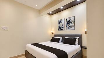 Quarto moderno com uma cama grande, duas luminárias na parede e arte abstrata.
