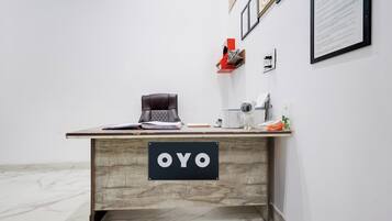 Uma mesa de madeira com uma placa indicando 'OYO' em um quarto com paredes brancas e piso de mármore.