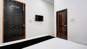 Quarto com cama, televisão na parede e duas portas.