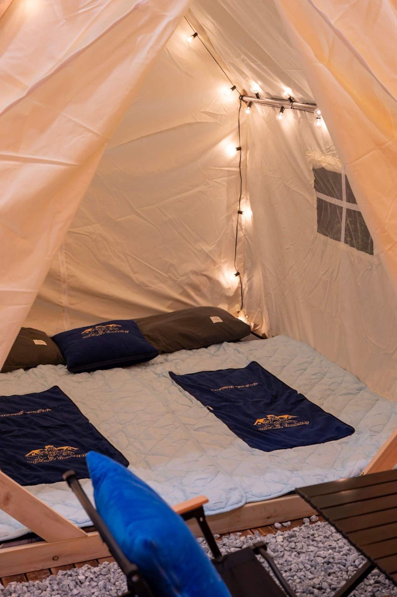 Uma tenda com cama, almofadas e luzes de cordão.