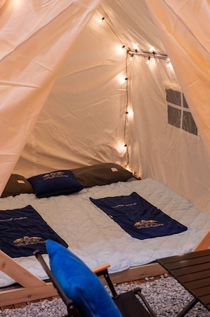 Uma tenda com cama, almofadas e luzes de cordão.