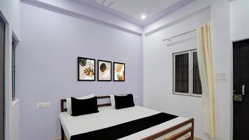 Quarto com cama, janela com cortina e três obras de arte emolduradas na parede.