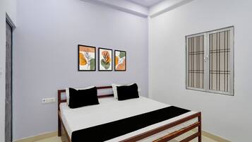 Quarto com cama, janela com grades e três obras de arte emolduradas na parede.