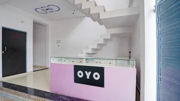 Interior moderno com escada, balcão de recepção com a inscrição 'OYO' e porta com o número '101'.