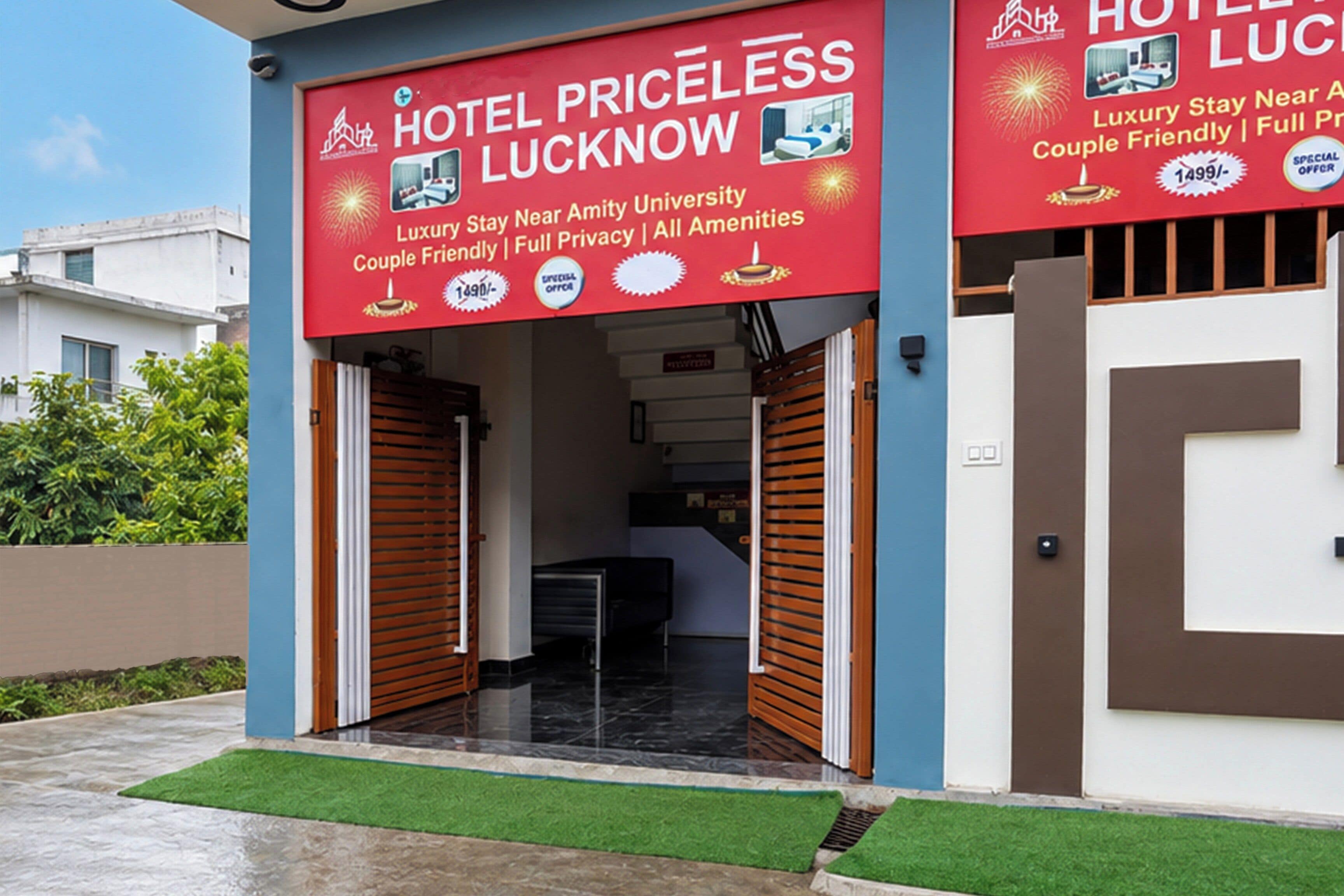 Entrada de hotel com uma placa vermelha anunciando 'Hotel Priceless Lucknow' e oferecendo acomodações de luxo, ideal para casais, privacidade total e todas as comodidades.