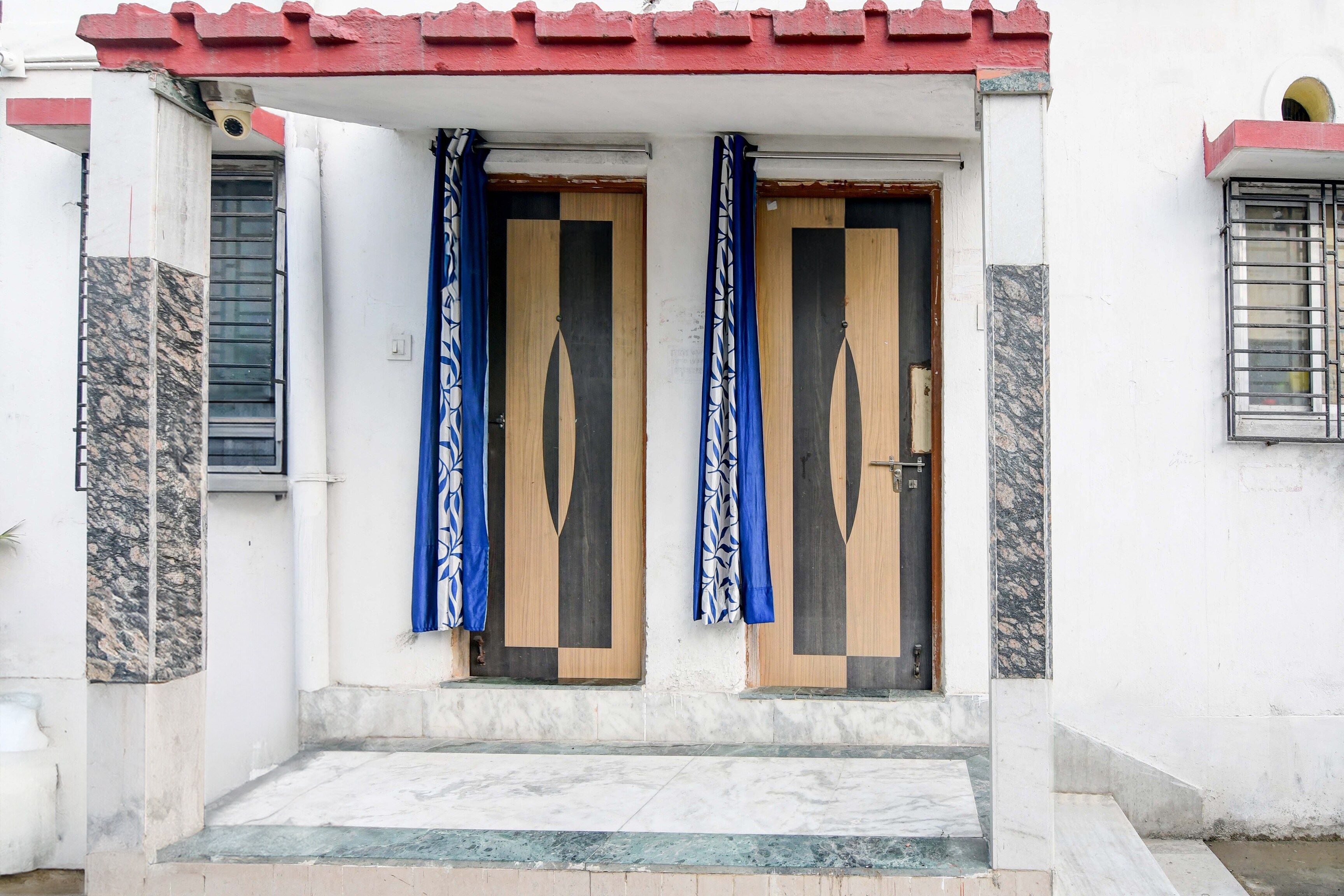 Um edifício com duas portas de madeira, um acesso revestido de azulejos e um telhado vermelho.