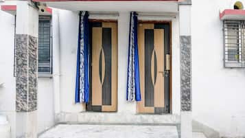 Um edifício com duas portas de madeira, um acesso revestido de azulejos e um telhado vermelho.