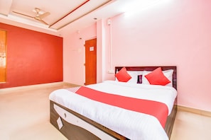 Quarto de hotel com cama, ventilador de teto e porta com uma placa.