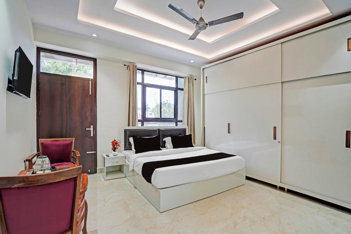 Quarto com cama, mesa de cabeceira, cadeira, guarda-roupa, ventilador de teto e janela.