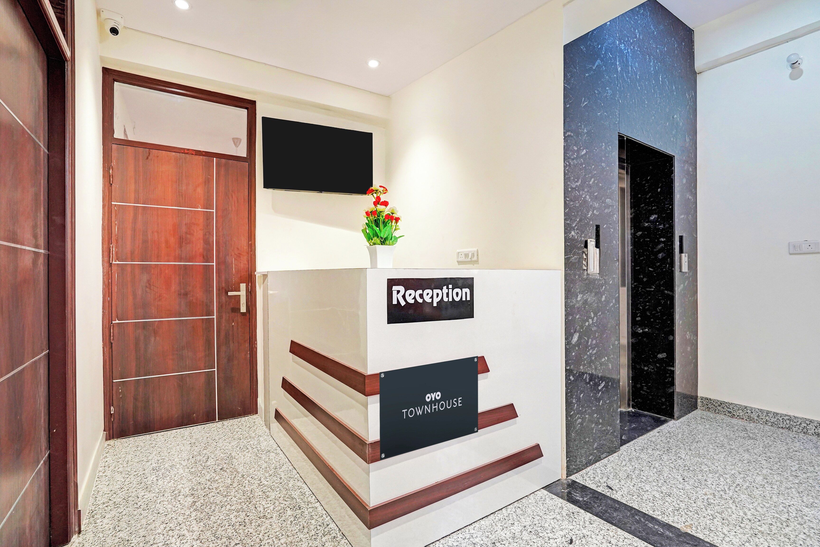 Uma mesa de recepção com uma placa que diz 'Reception' e 'OYO TOWNHOUSE'.