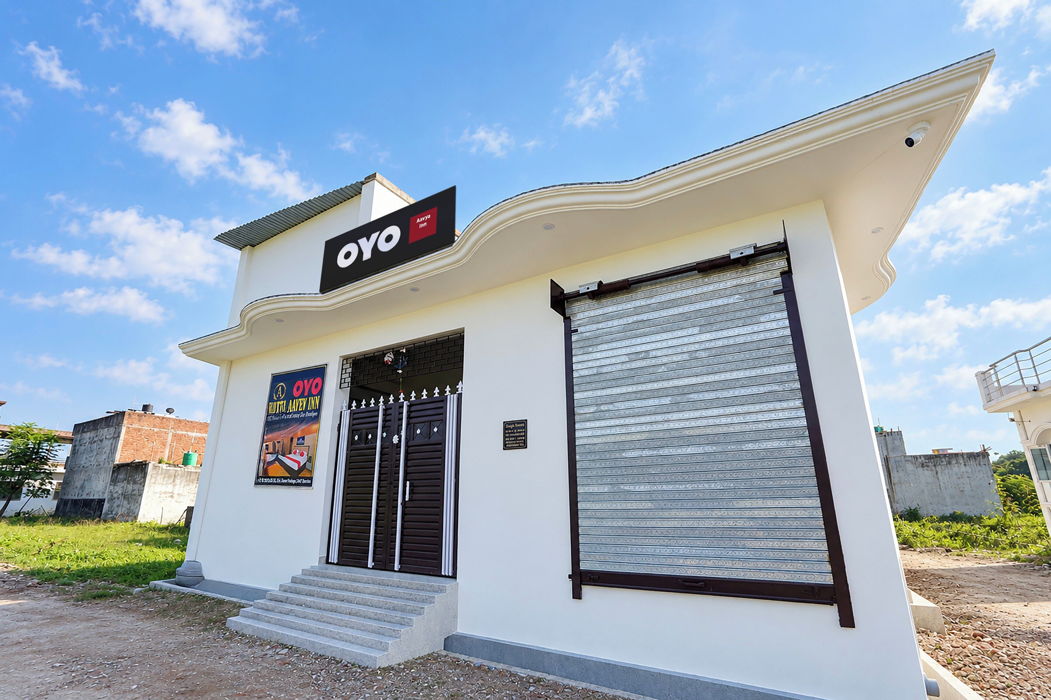 Um hotel chamado 'OYO' com design moderno, destacando uma entrada imponente e uma grande janela com persiana.