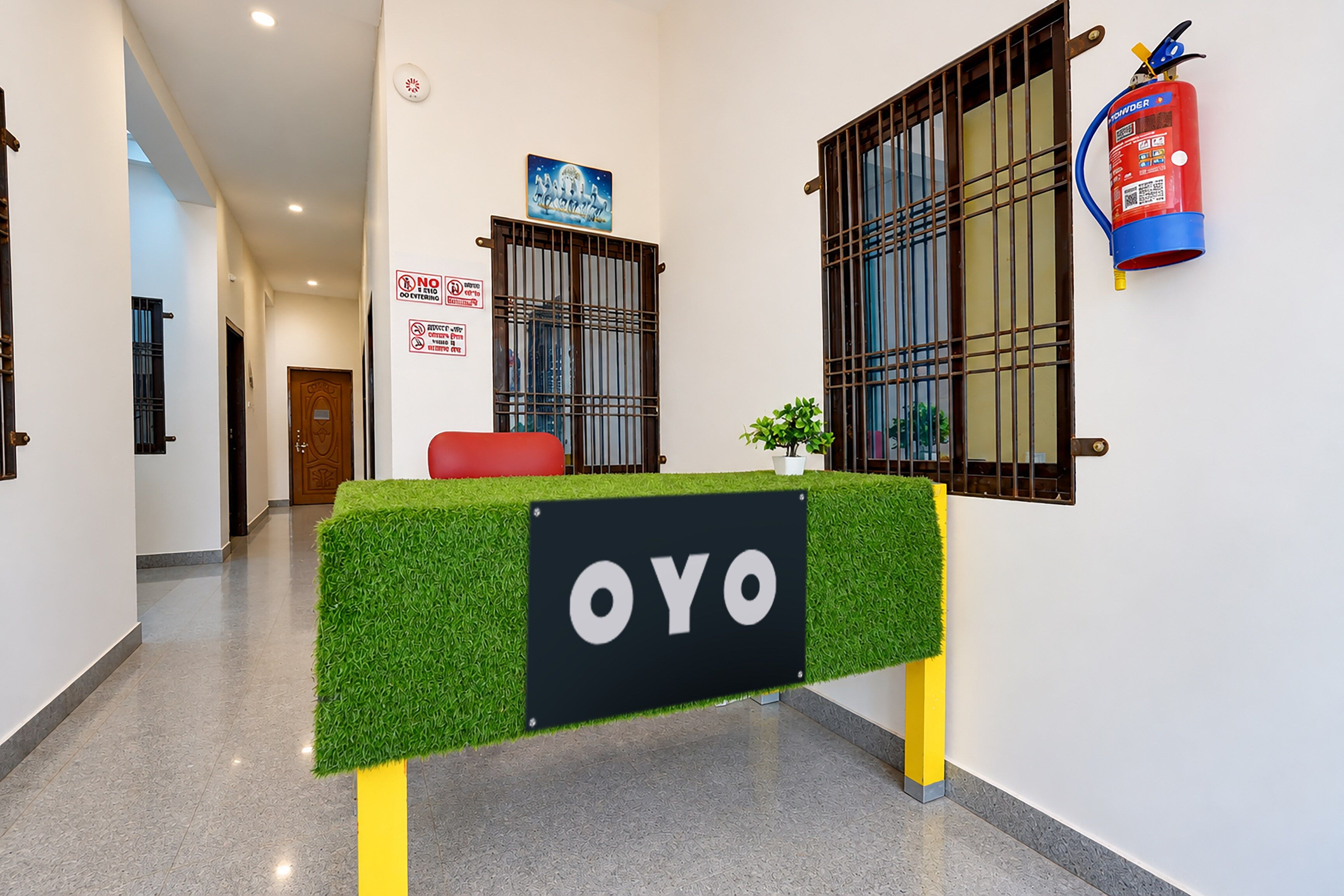 Balcão de recepção com uma placa que diz 'OYO' no saguão de um hotel.