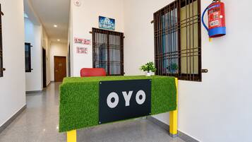 Balcão de recepção com uma placa que diz 'OYO' no saguão de um hotel.
