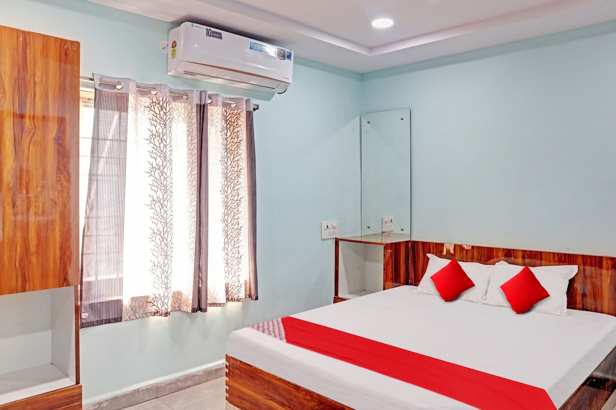 Quarto de hotel com uma cama, espelho, aparelho de ar condicionado e cortinas.