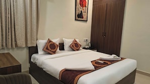 Quarto de hotel com cama, mesa de cabeceira, guarda-roupa e um quadro na parede.