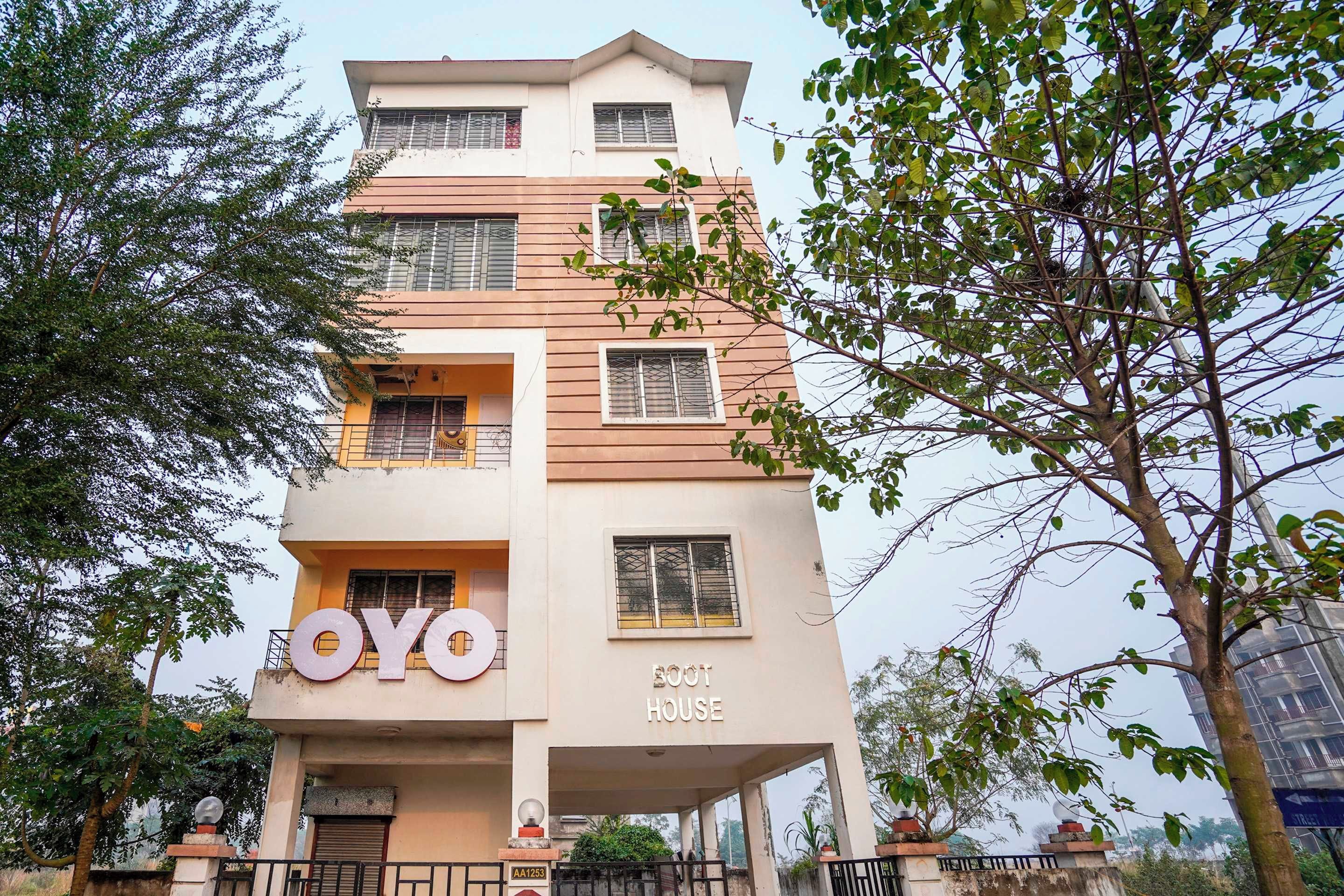 Um edifício de vários andares com uma placa indicando 'OYO BEST HOUSE' e o número 'AA1253' visível.
