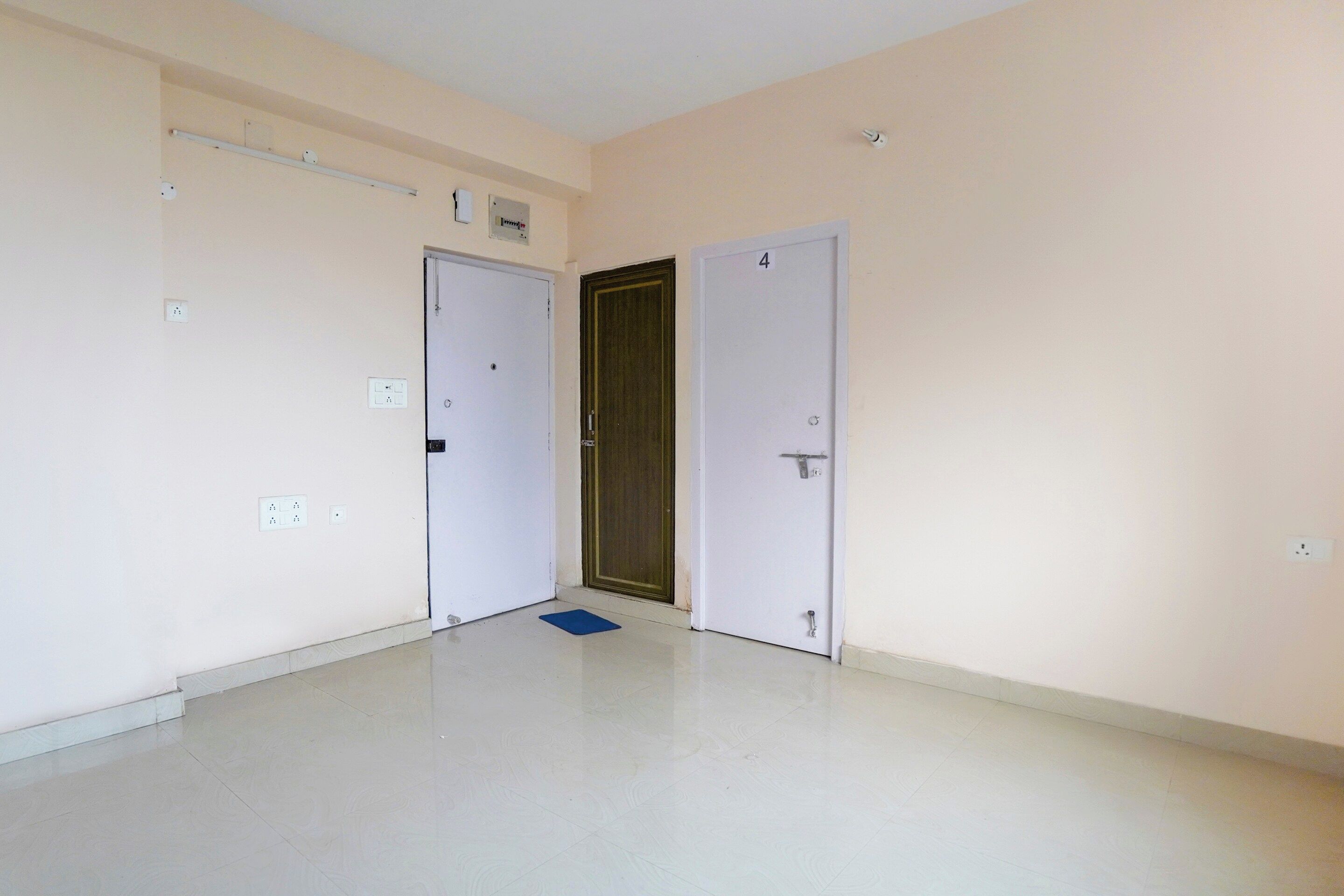 Um corredor com duas portas brancas, uma delas com o número 4, e um tapete azul no chão.