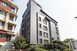 Edifício de vários andares com uma placa grande 'OYO TOWNHOUSE', apresentando um design arquitetônico moderno com janelas amplas e varandas.