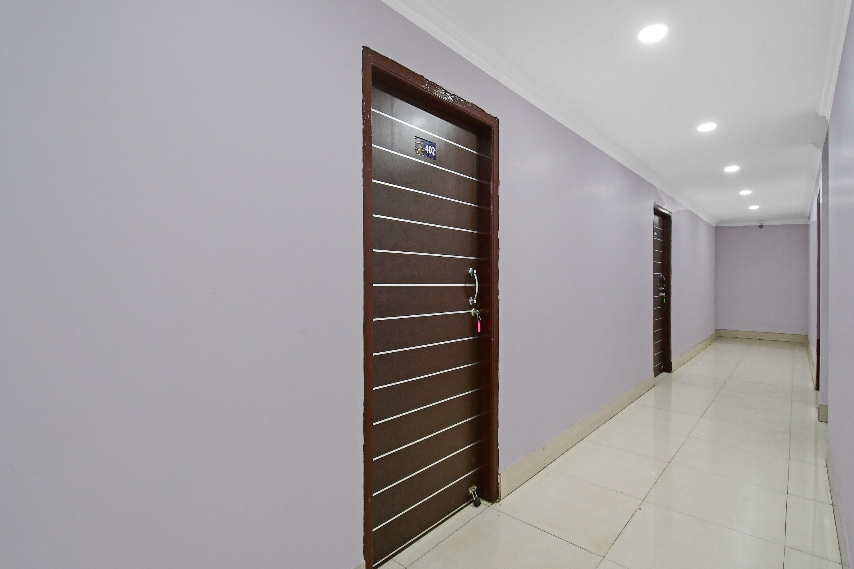 Corredor com porta, detalhando barra metálica horizontal e olho de fechadura.