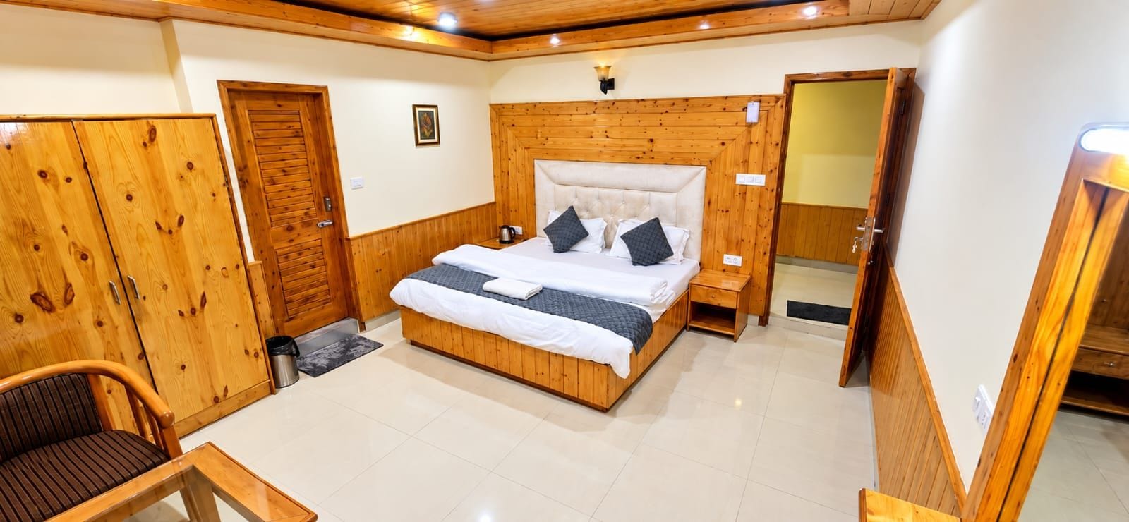 Quarto com cama de madeira, uma cadeira e um guarda-roupa.