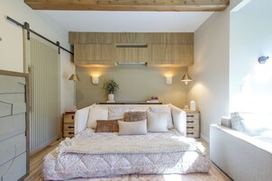 Quarto com cama, mesas de cabeceira, luminárias na parede e uma janela.