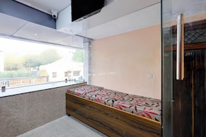 Quarto moderno com um banco, divisória de vidro e vista para o exterior.