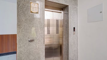 Elevador em um saguão de hotel, com uma placa acima.