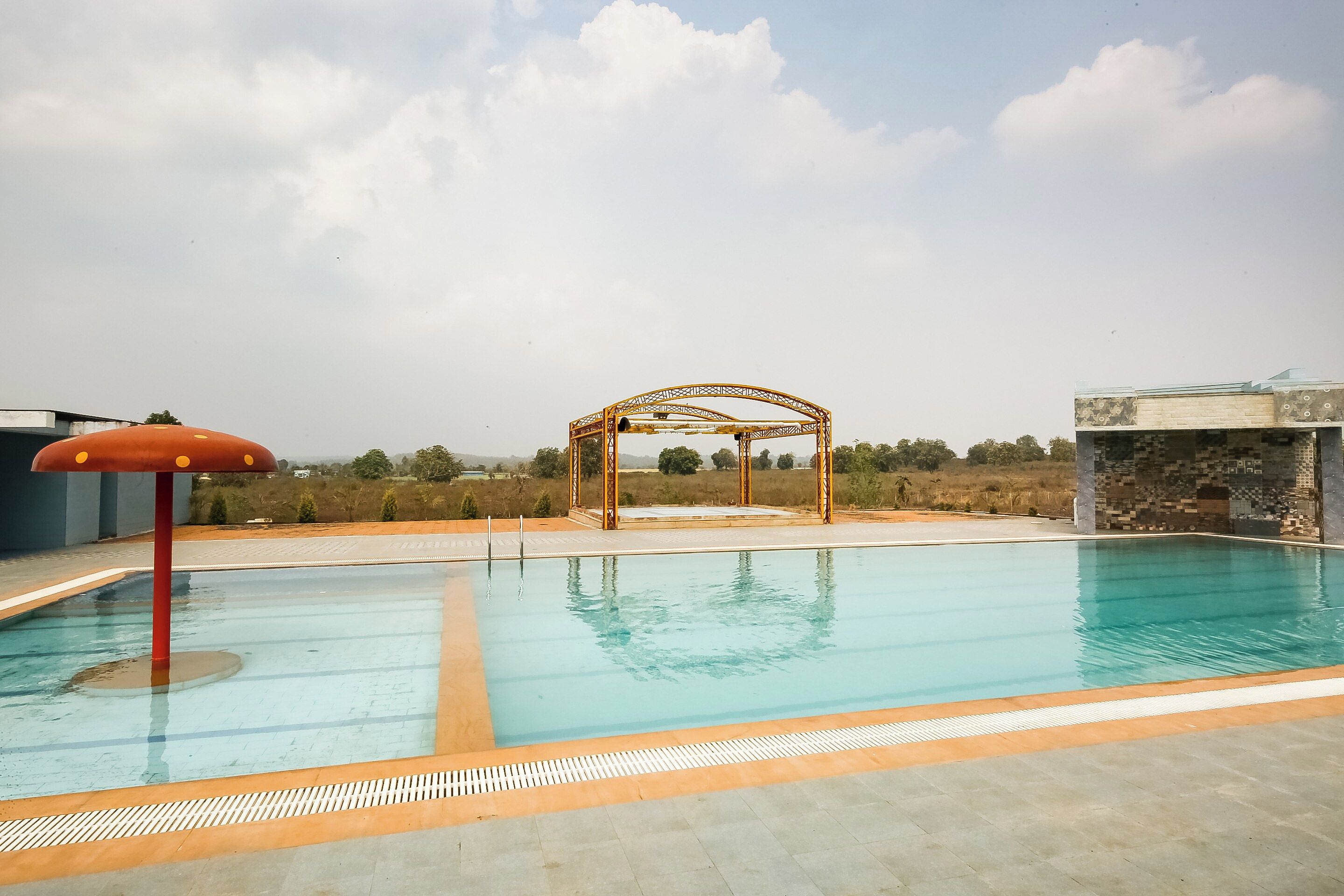 Piscina com estrutura de pérgola ao fundo.