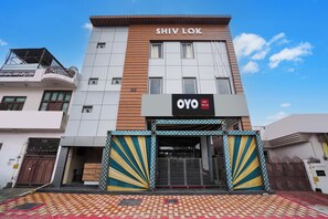 Um hotel chamado Shiv Lok com fachada moderna, uma placa de destaque e entrada com padrão.